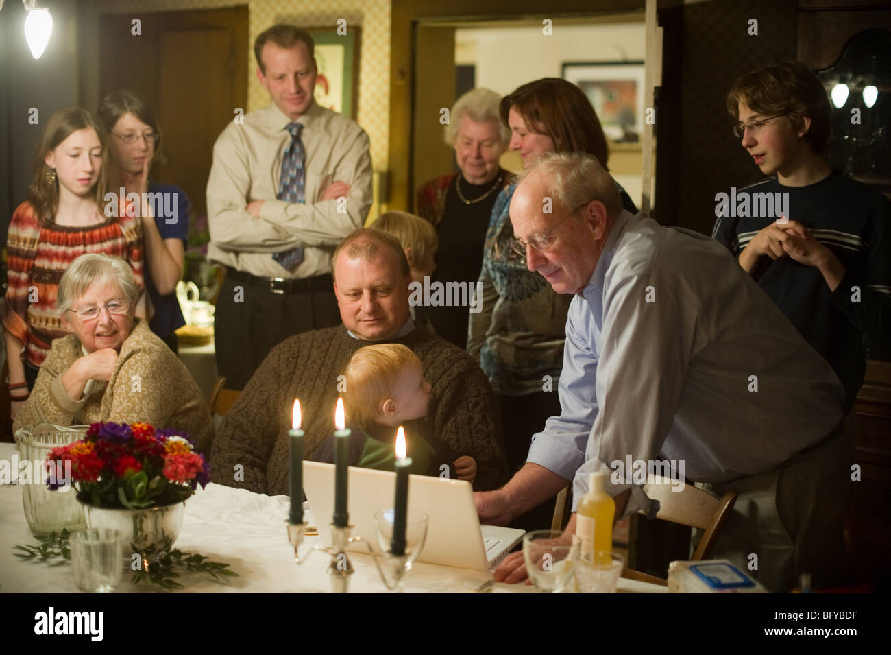 Family gathered around laptop computer at family dinner Stock Photo - Alamy