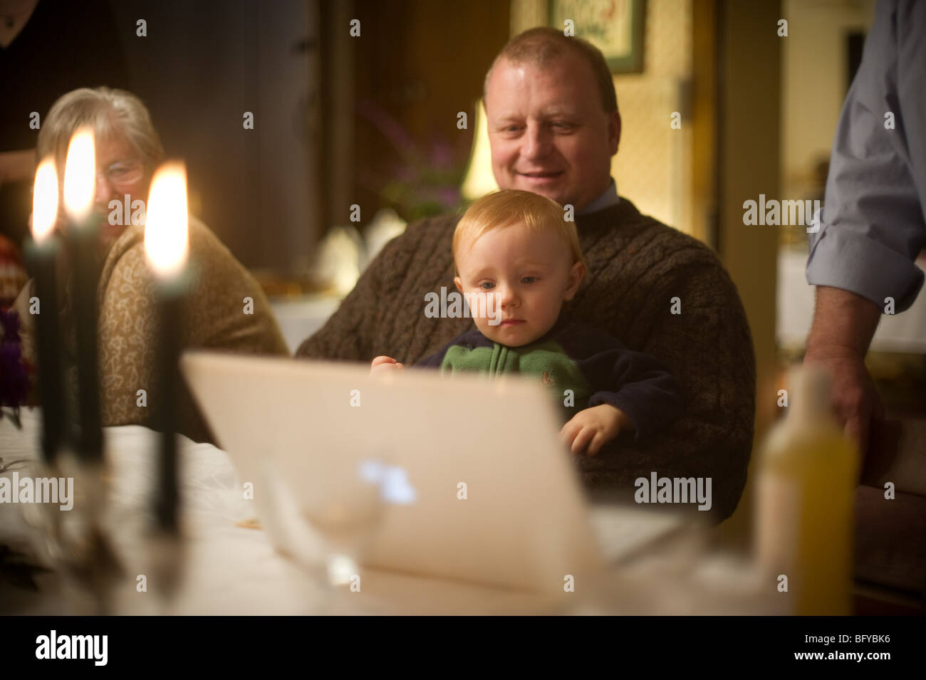 Family gathered around laptop computer at family dinner Stock Photo - Alamy