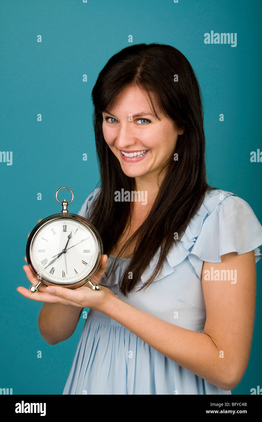 Woman holding clock and smiling Stock Photo - Alamy