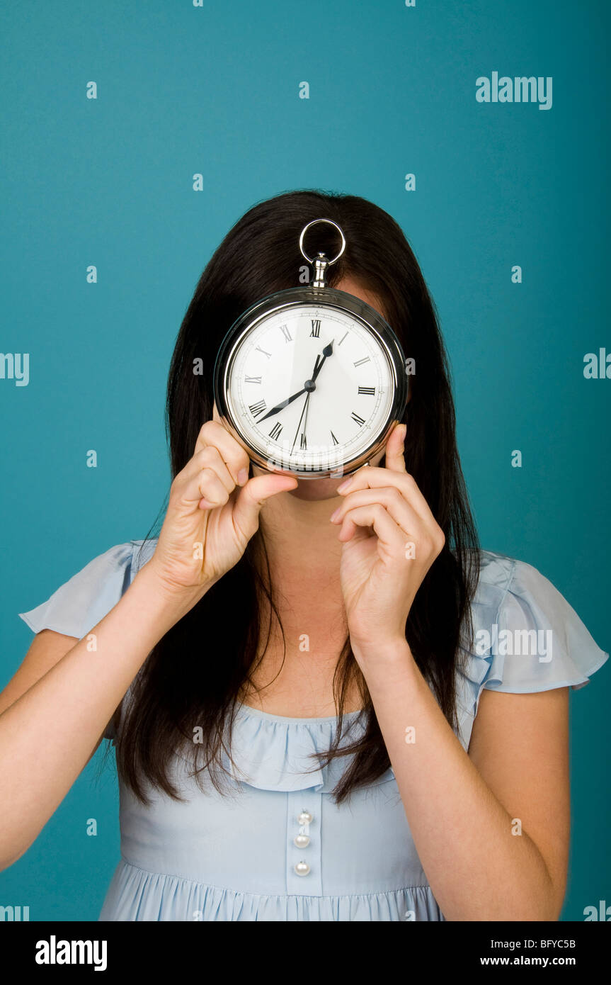 Woman covering face with clock Stock Photo - Alamy