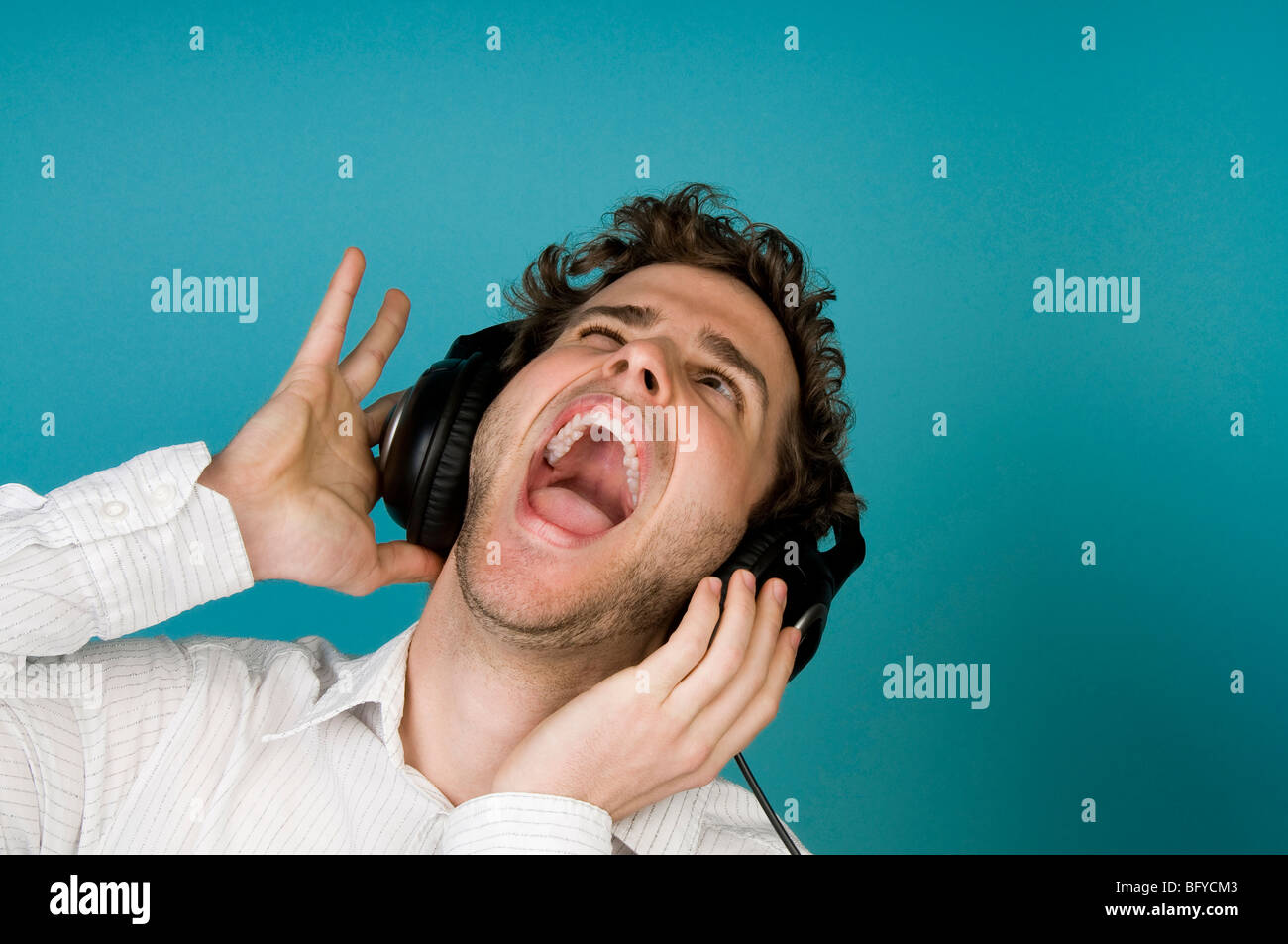 Man listening to headphones and screaming Stock Photo - Alamy