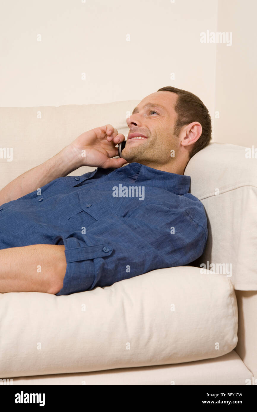 Man relaxing at home, talking on his mobile phone Stock Photo - Alamy