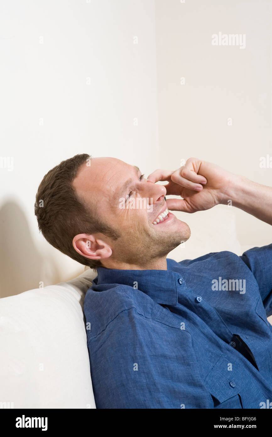 Man relaxing at home, talking on his mobile phone Stock Photo - Alamy