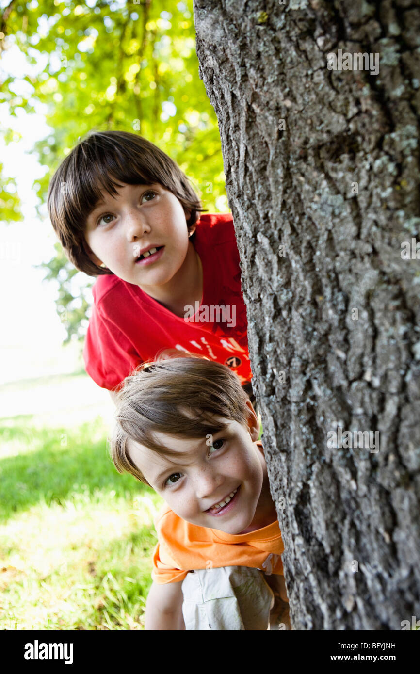 Two Boys Hiding Behind Tree Close-Up Stock Photo - Alamy