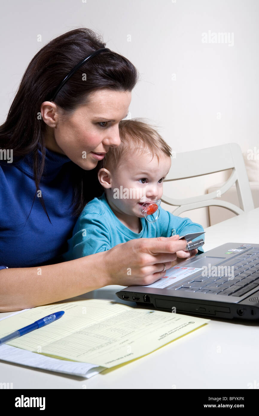 Mother paying bills online, with baby boy on her lap Stock Photo - Alamy
