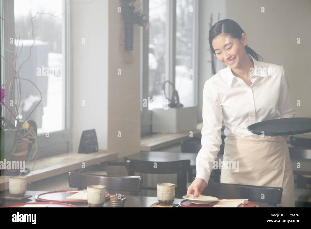 portrait of young japanese waitress setting table at restaurant Stock ...