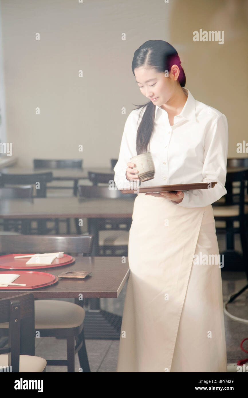portrait of young japanese waitress setting table at restaurant Stock ...