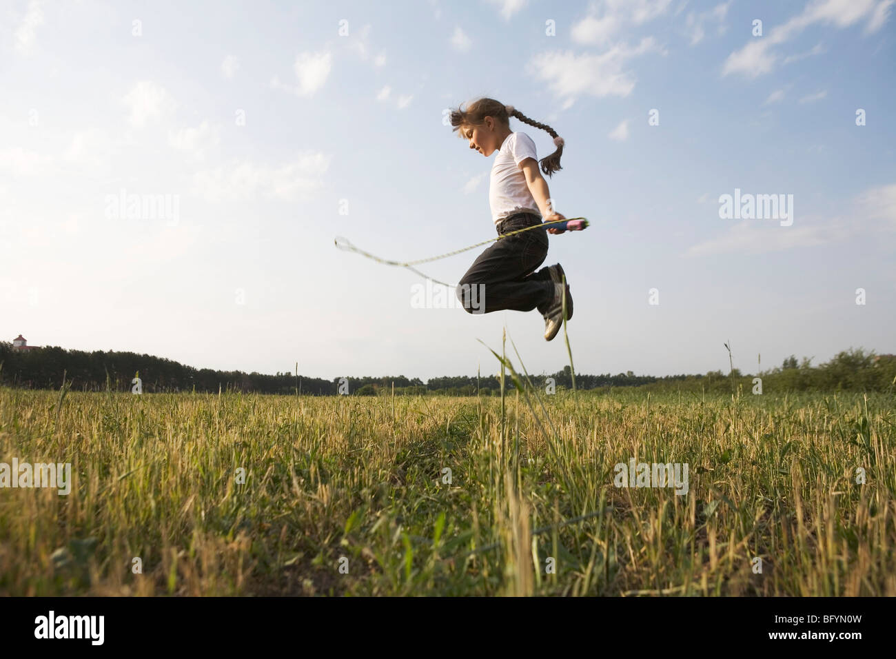 young girl skipping in field Stock Photo - Alamy