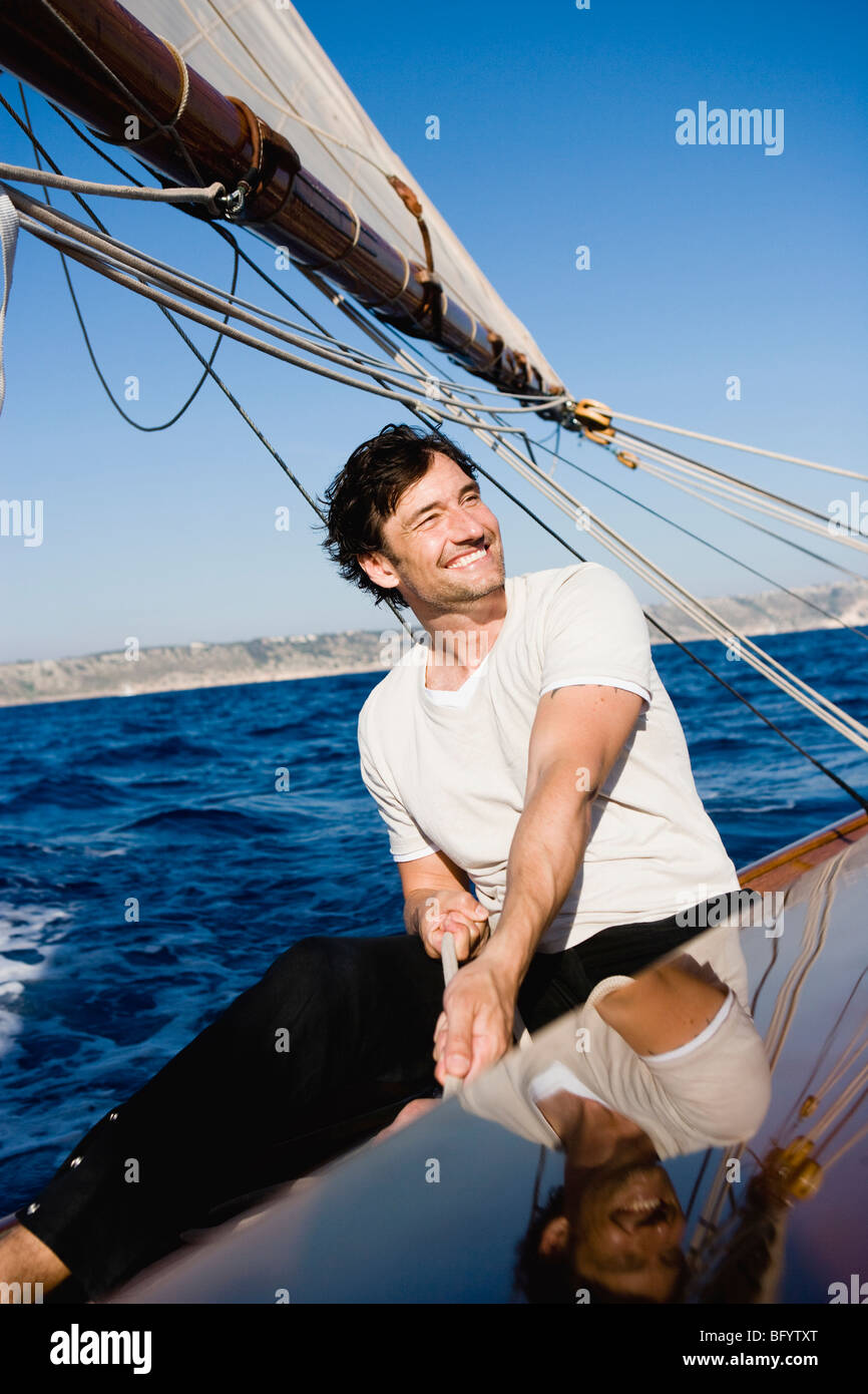 man smiling steering a sailing boat Stock Photo - Alamy