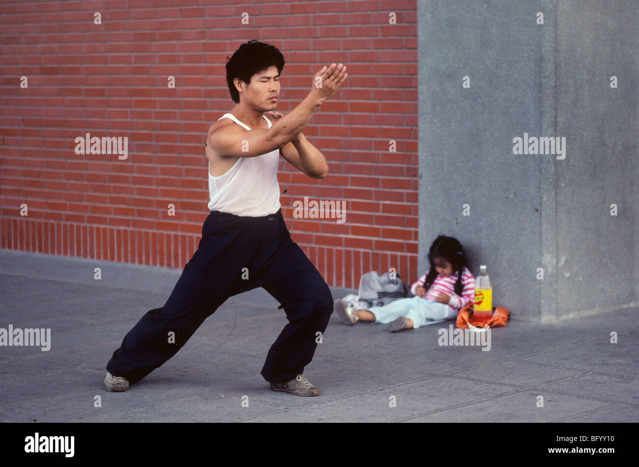 A young daughter waits for her father to complete his tai chi routine ...