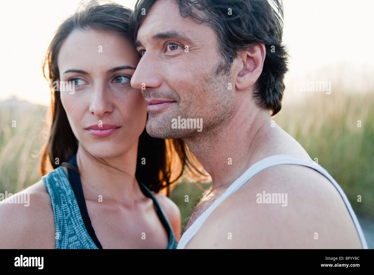 couple embracing looking around at beach Stock Photo - Alamy