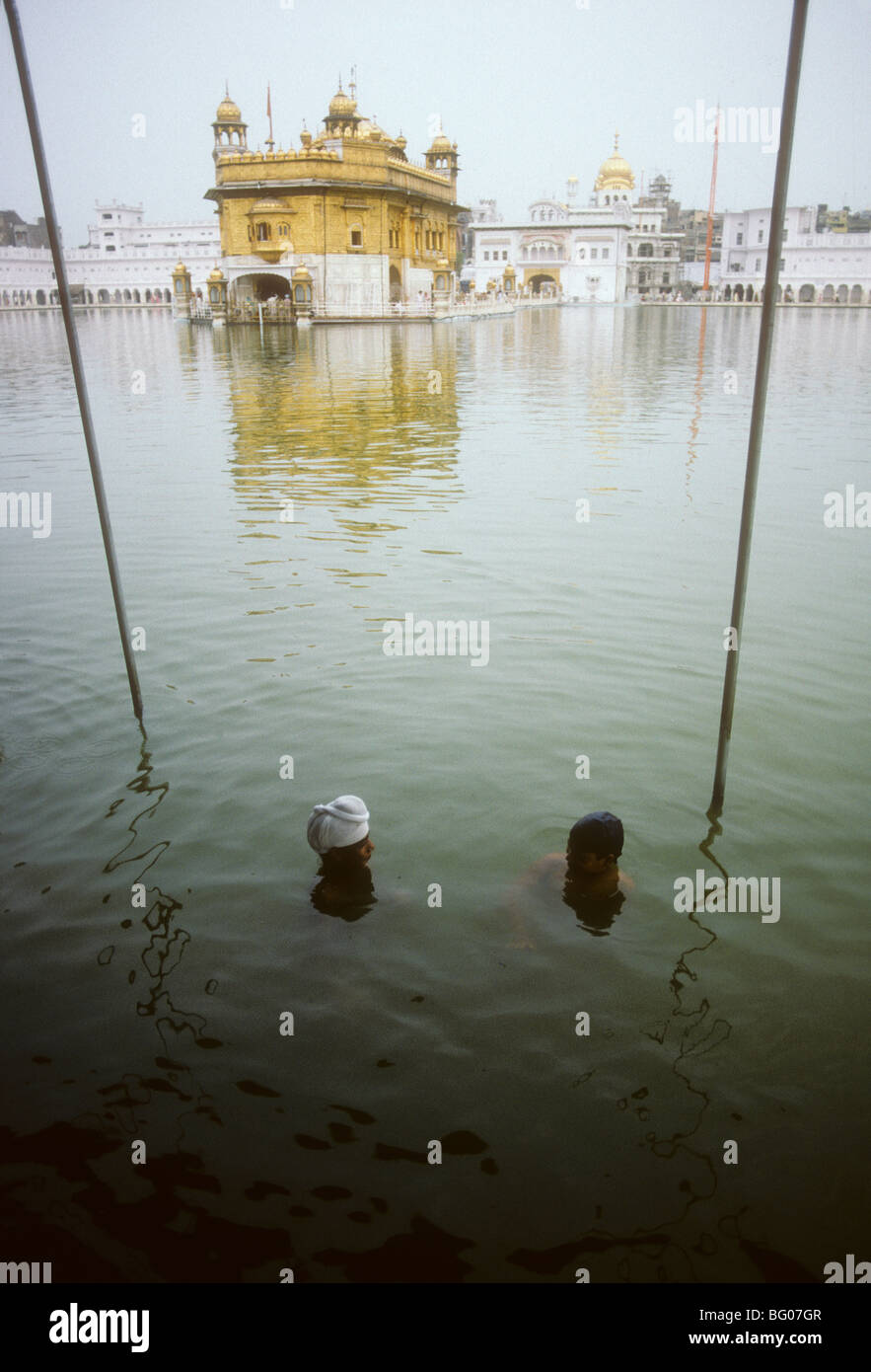 Two Sikh pilgrim bathe in the water surrounding the Golden Temple ...