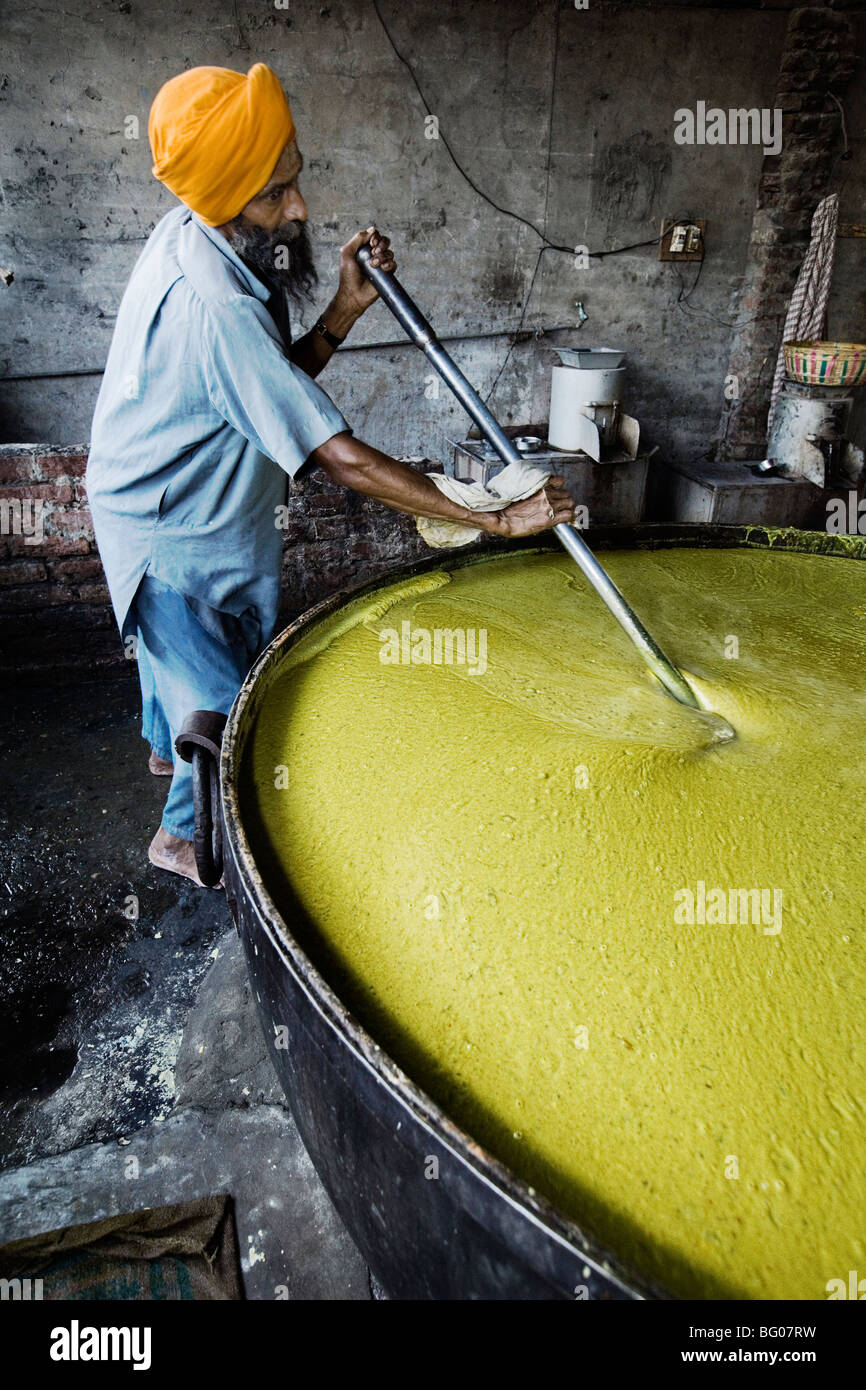 Sikh man cooking hufe bowl of lentil soup in the communal kitchen of ...