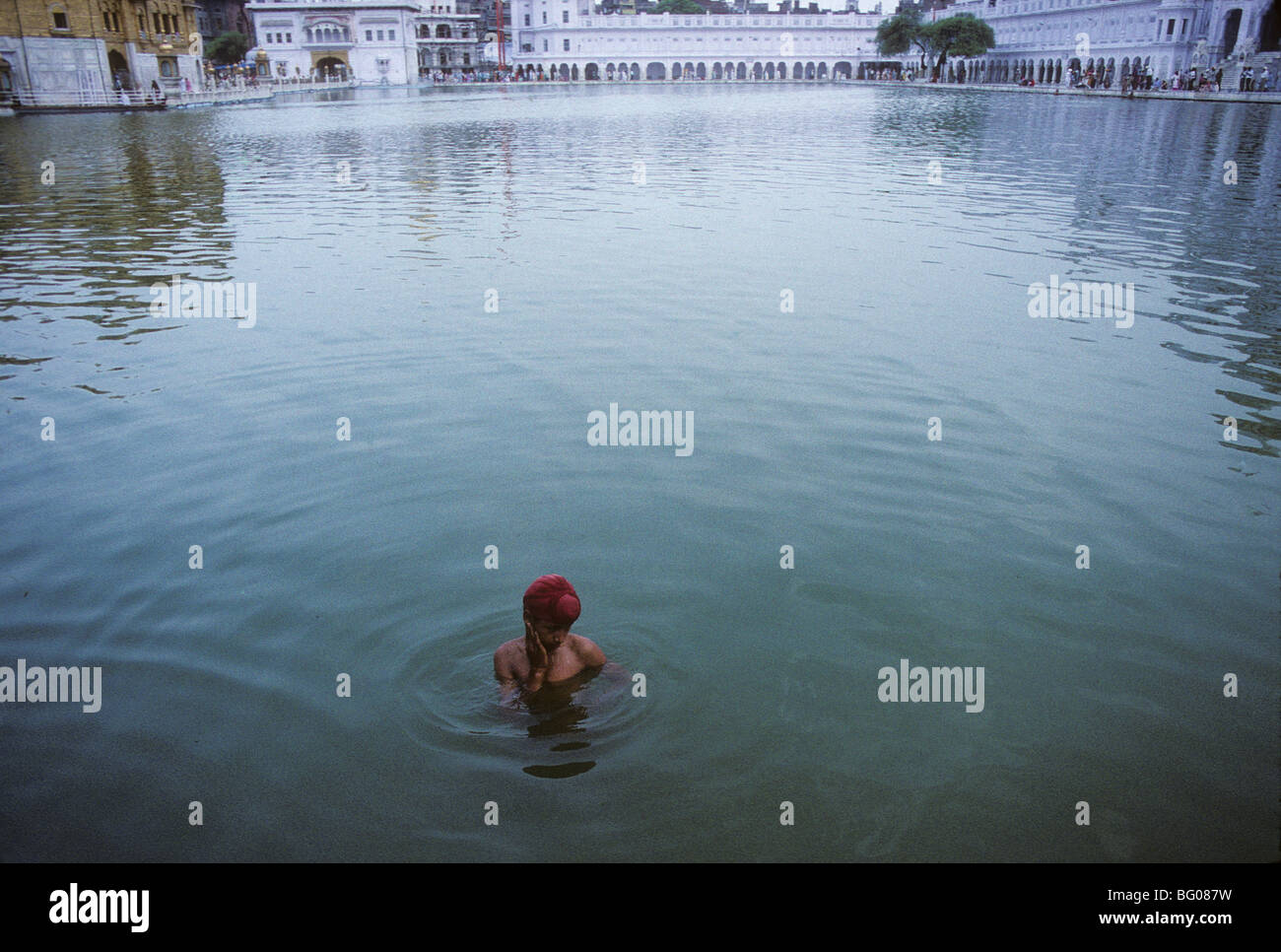 A young Sikh man bathes at dawn in the water that surrounds the Golden ...