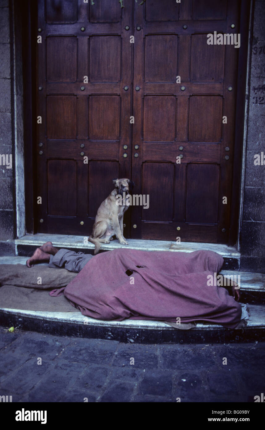 Two sleeping people and one awake dog on the streets of Mumbai, India ...
