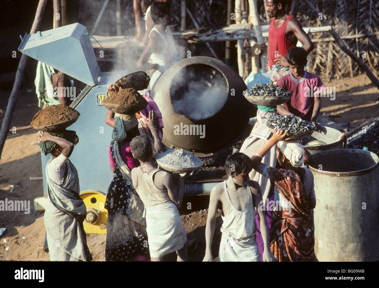 Women and child laborers making cement concrete at a construction site ...