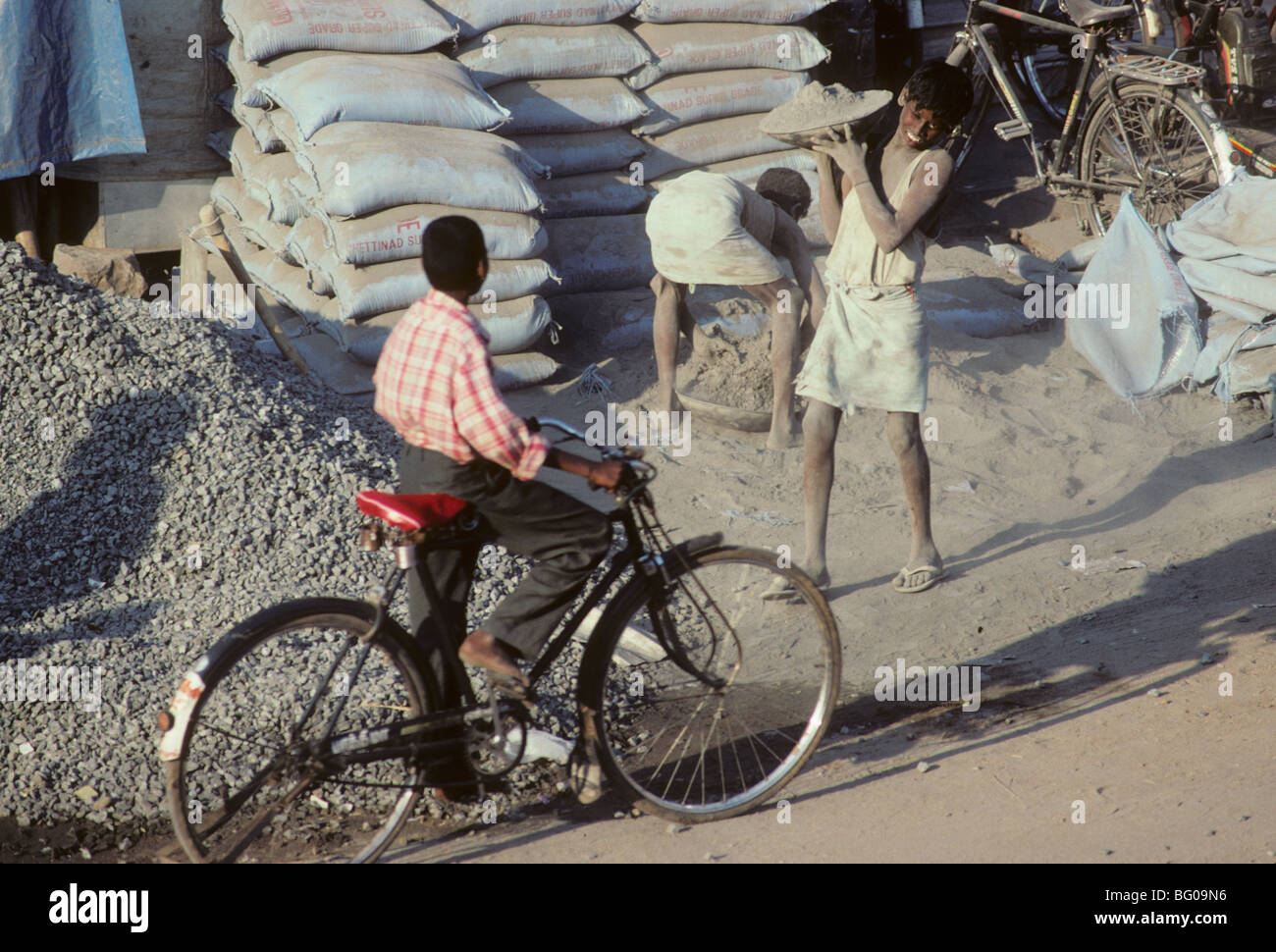 Two young boy child laborers bring sand to make cement concrete at a ...