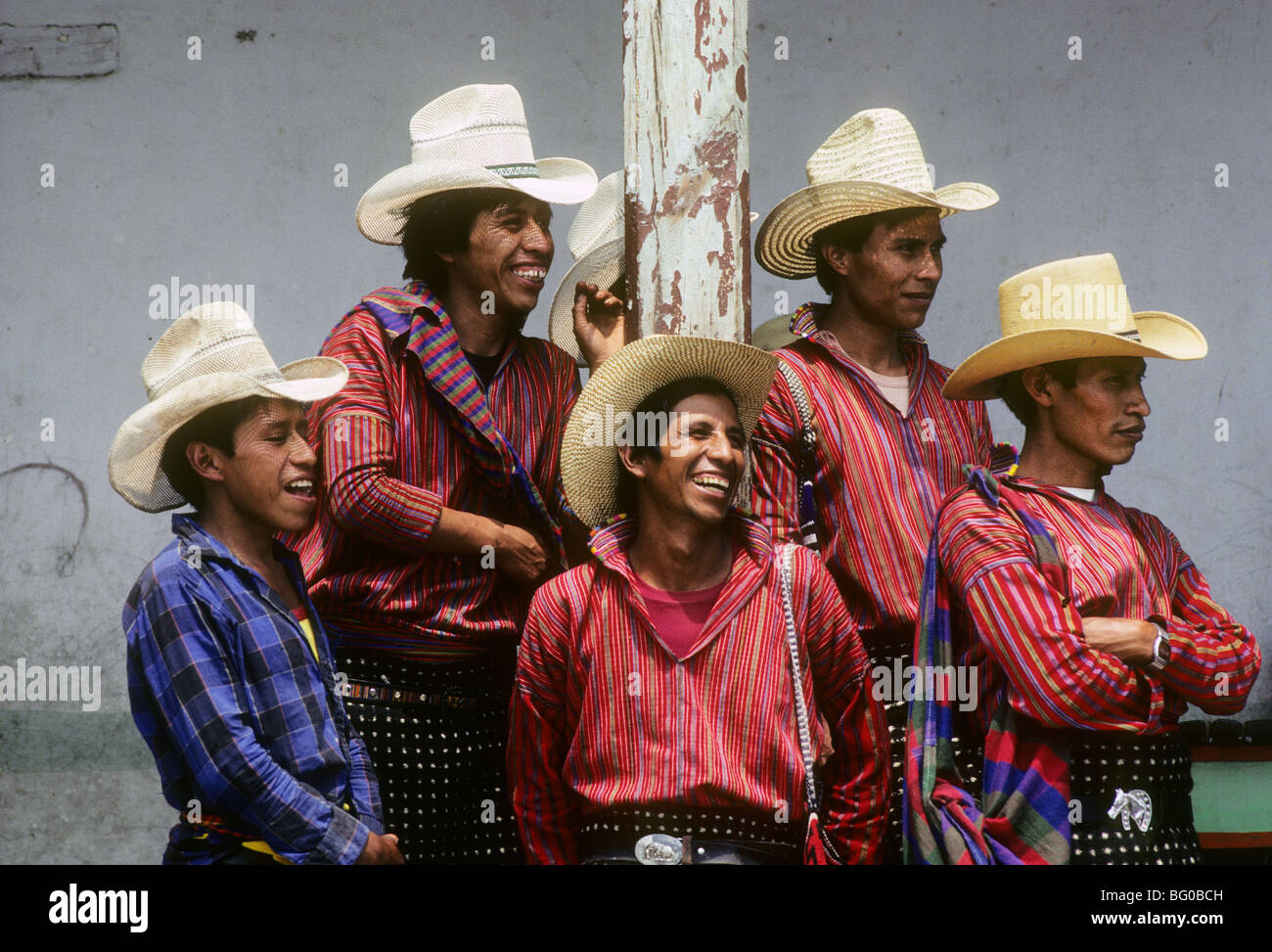 A group of Guatemalan men laugh while watching the antics of children ...