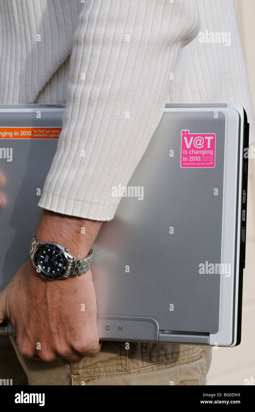 VAT changes for 2010 Man holding laptop computer with reminder on VAT ...
