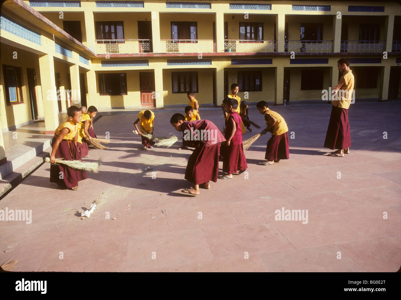 Young Buddhist monk students sweep the courtyard of their school in ...