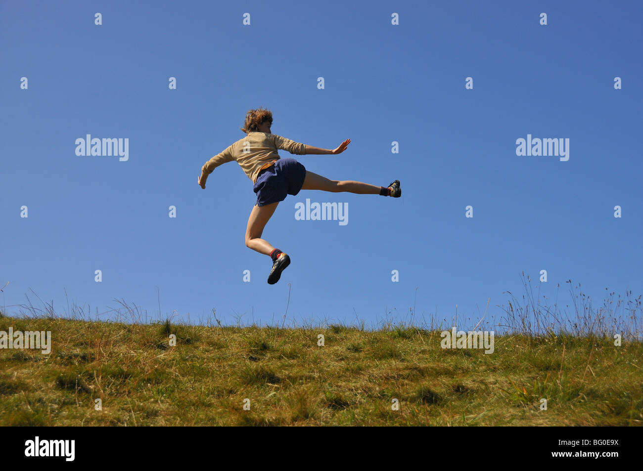 young white woman jumping and leaping on the dune arms up and legs in ...