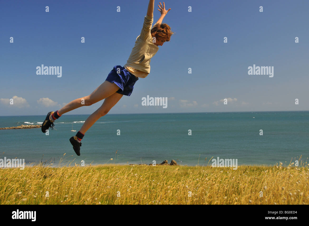 young white woman jumping and leaping on the dune arms up and legs in ...