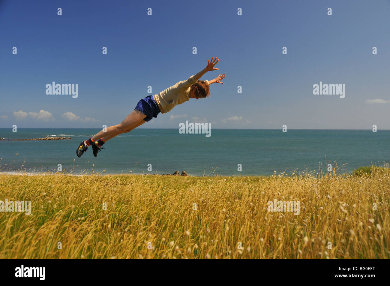 young white woman jumping and leaping on the dune arms up and legs in ...