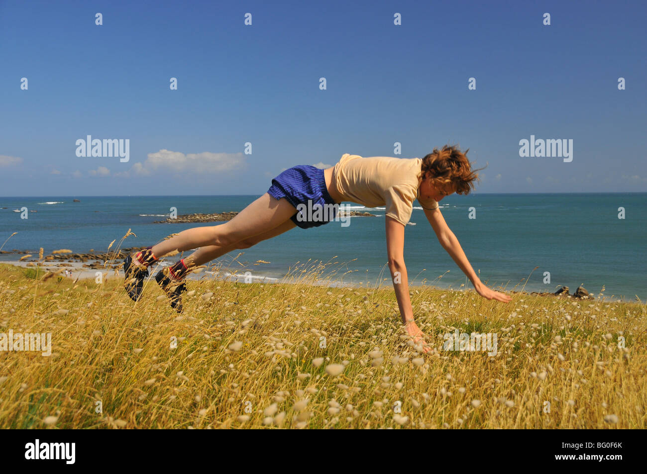 young white woman jumping and leaping on the dune legs above ground in ...
