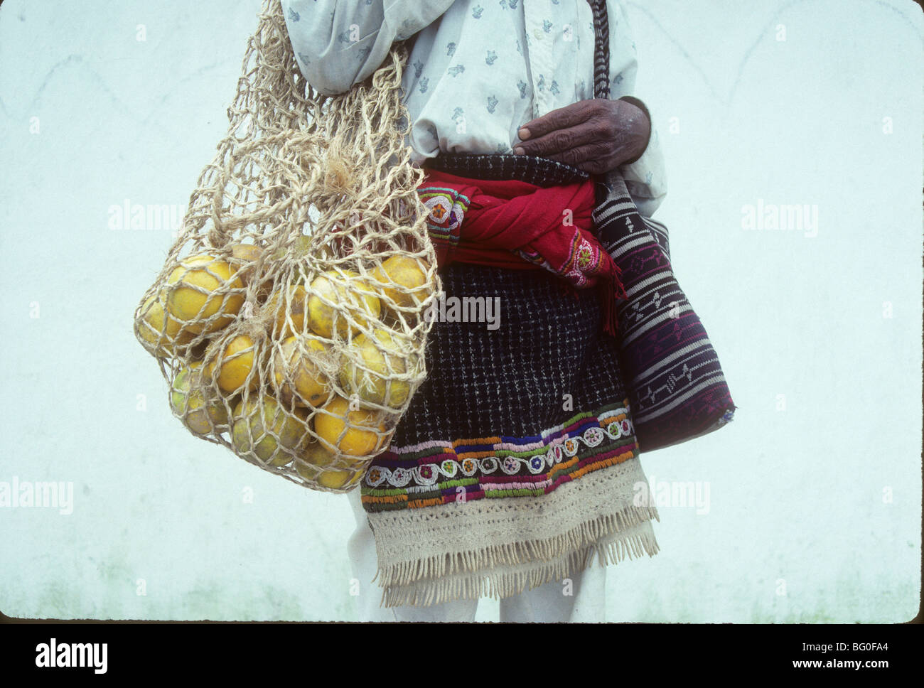 A man wearing traditional clothing including shoulder bag with oranges ...