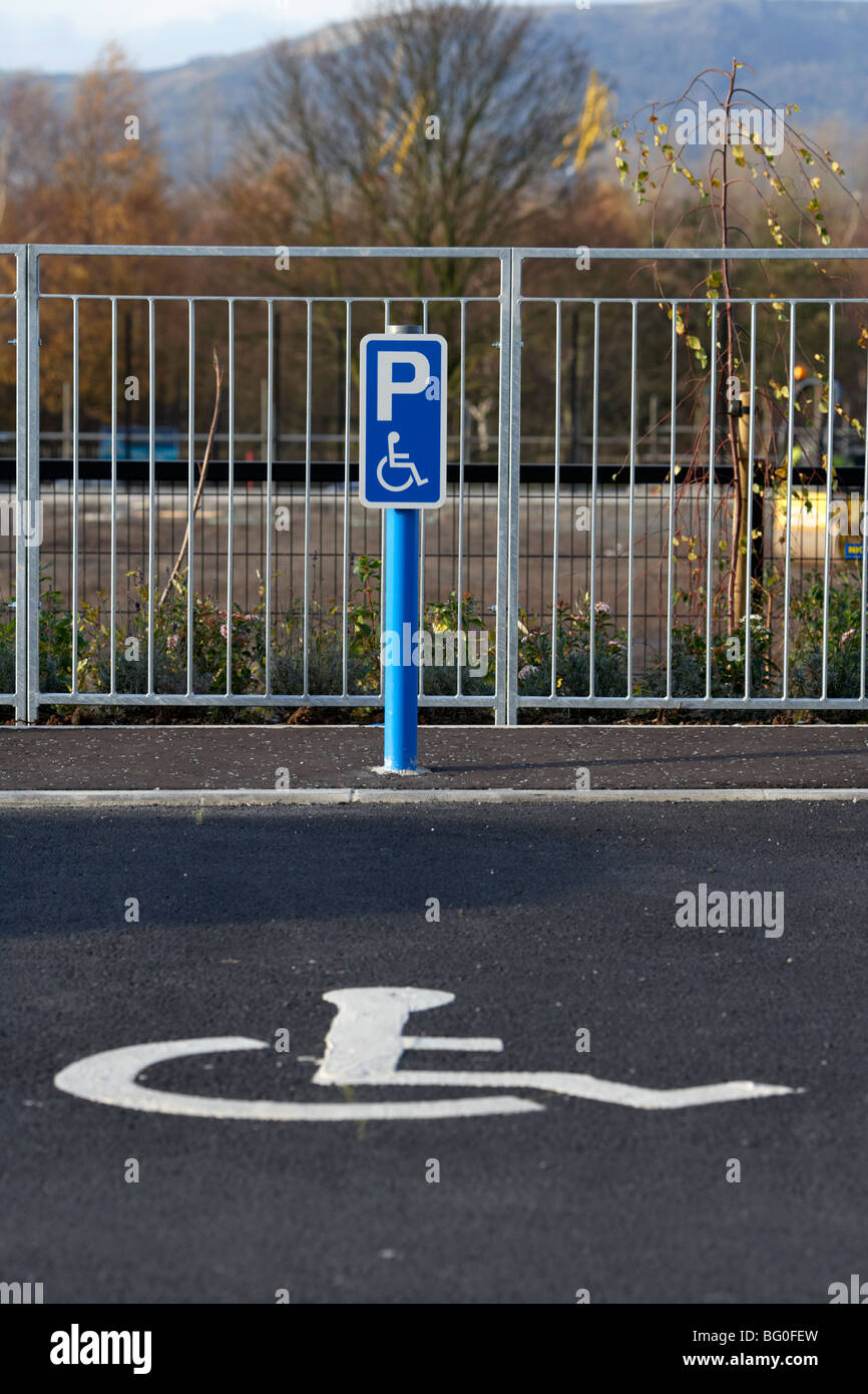 post with disabled parking sign in front of a parking bay in a car park ...