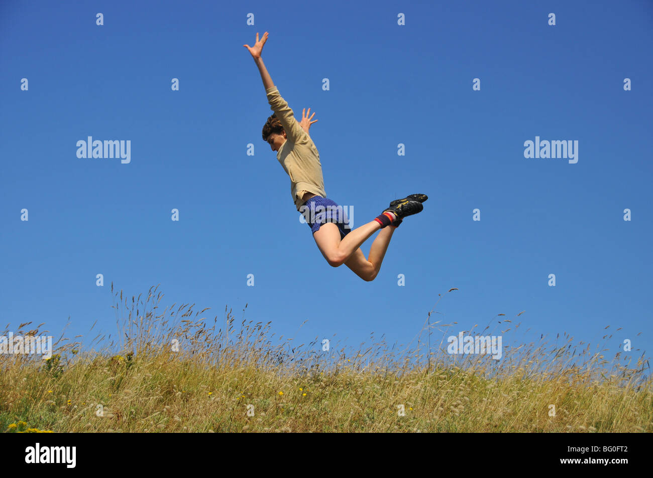 young white woman jumping and leaping on the dune arms and legs in air ...