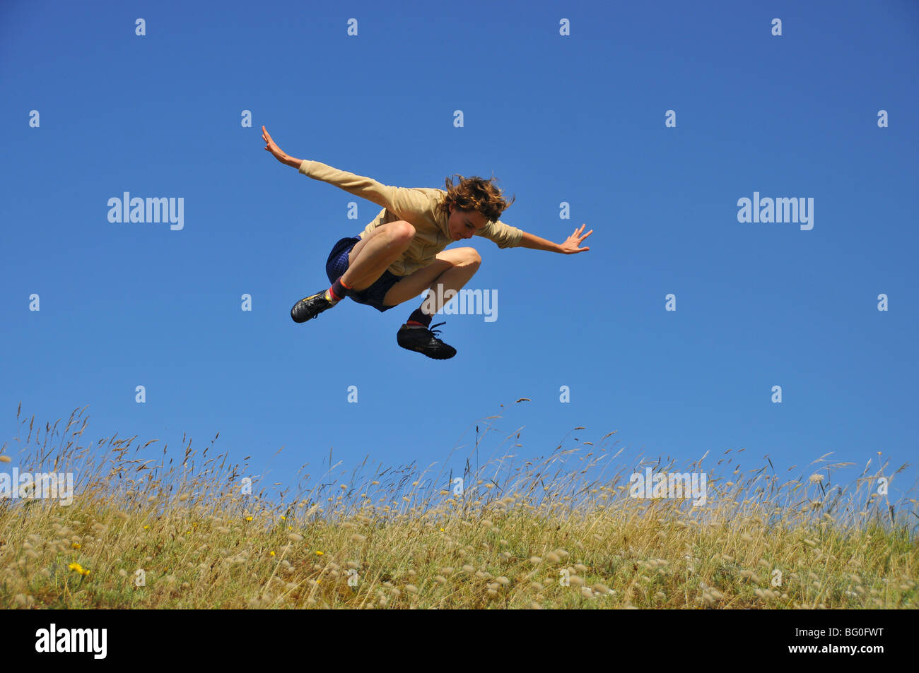 young white woman jumping and leaping on the dune arms and legs in air ...