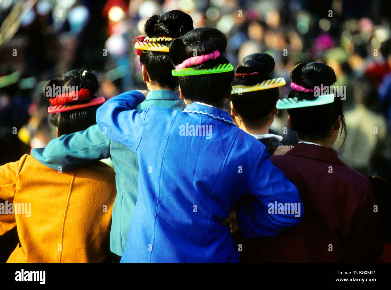 Five Miao women with colorful combs in their hair watch fesival dances ...