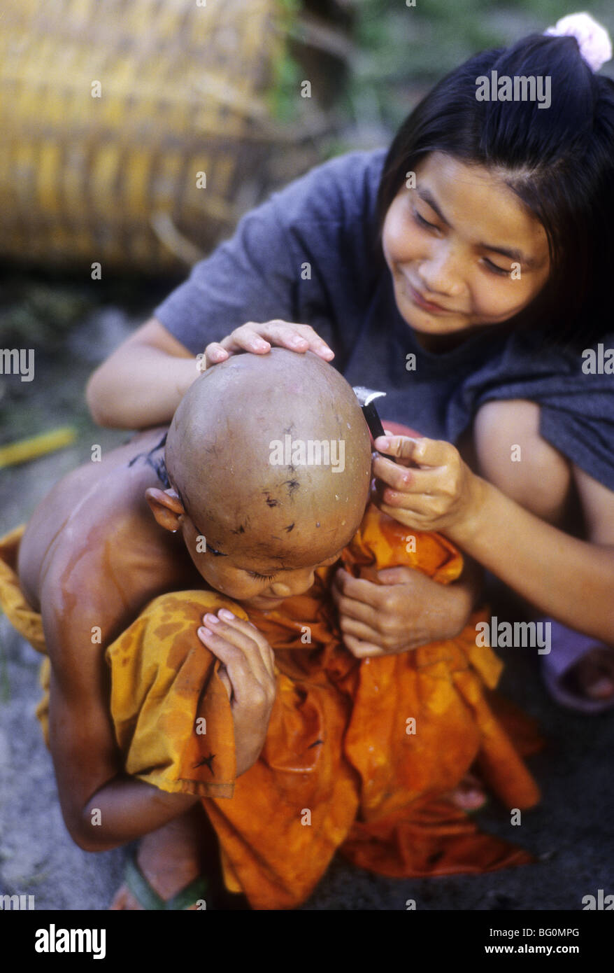 A young student monk gets his head shaved by his sister at a Buddhist ...