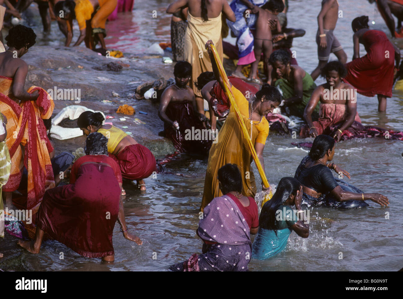 Women bathe and wash their saris in the Ganges River at Varanasi, India ...