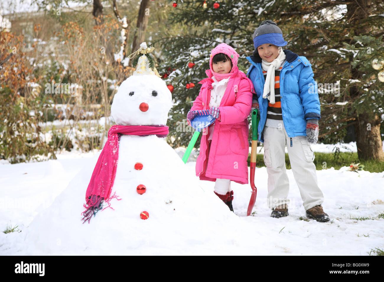 boy and girl next to snowman Stock Photo - Alamy