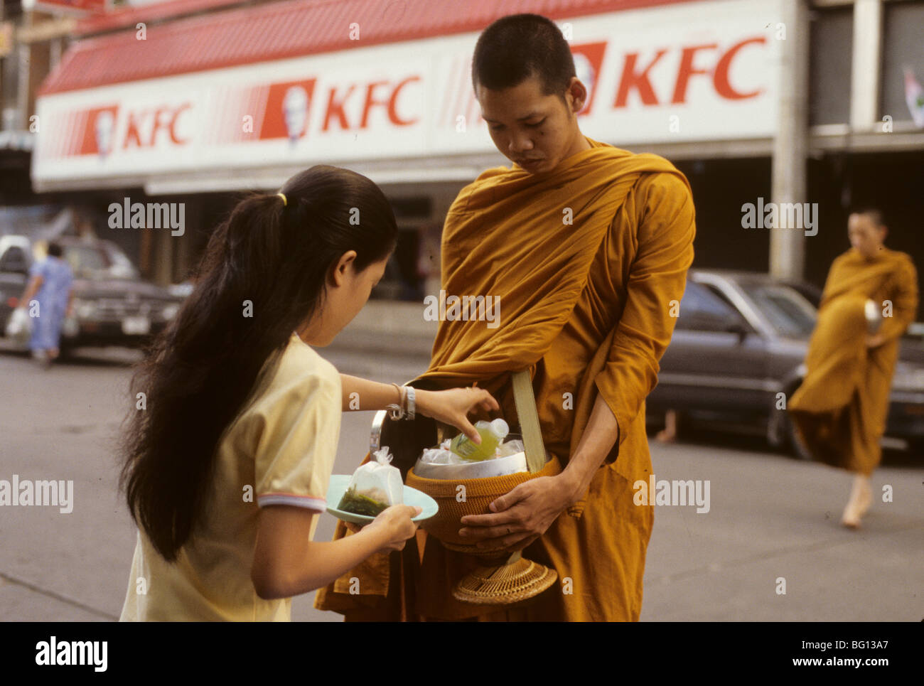 A Buddhist monk receives alms in front of a Kentucky Fried Chicken fast ...