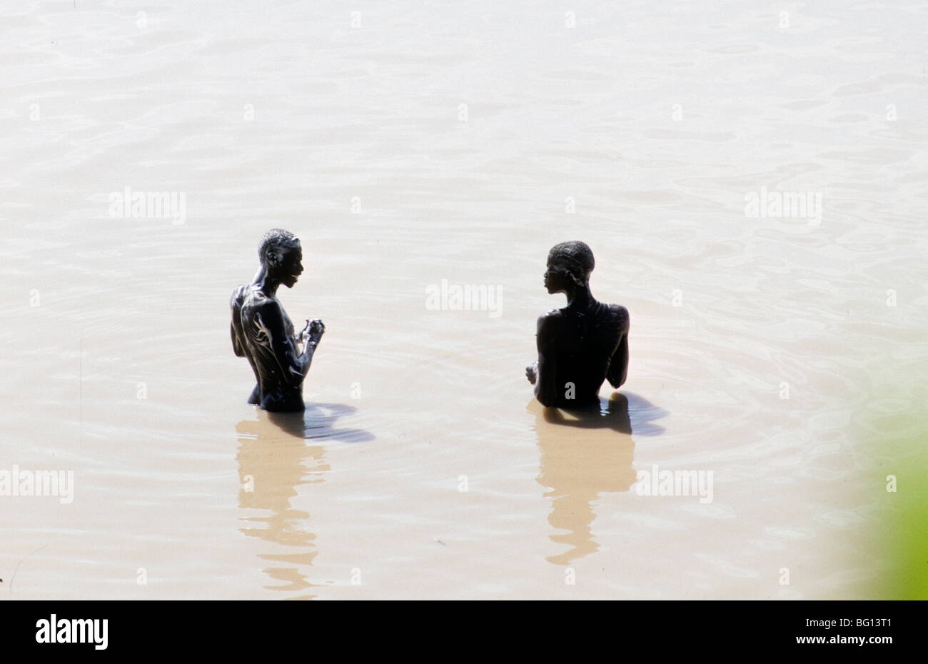 Two young men have a conversation while bathing in the Niger River in ...