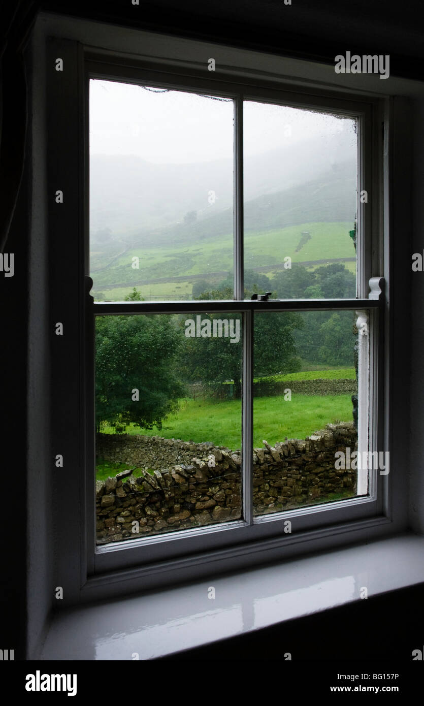 Traditional window frame looking out onto fells and grassland of Lake ...