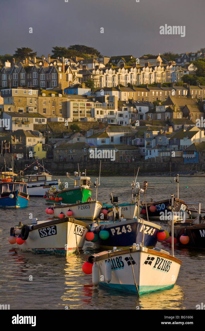 A stormy sky at sunset with small Cornish fishing boats in the harbour ...
