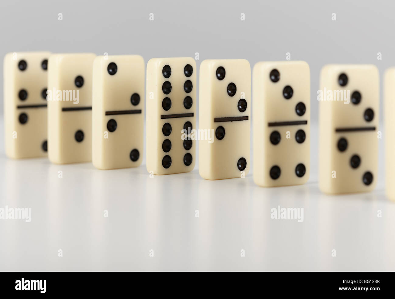 Dominoes line up on a grey surface Stock Photo - Alamy