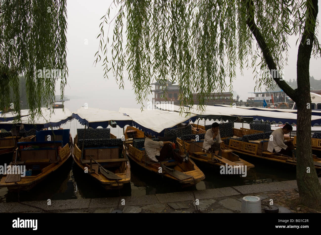 Hangzhou, West Lake, China. Boatmen waiting for tourists on a rainy day ...