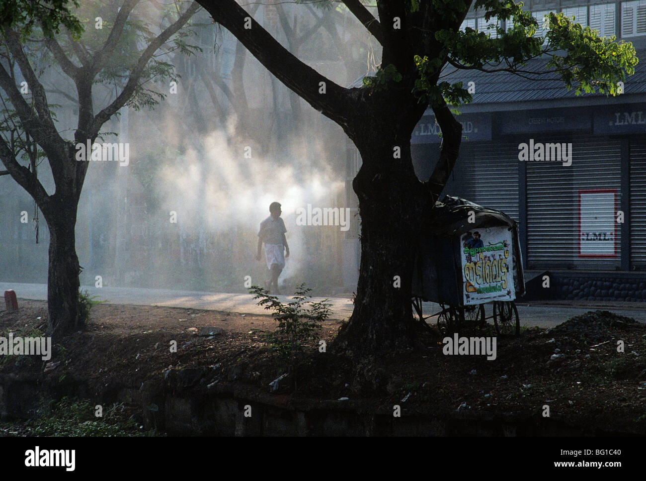 A man walks through some smoke caused by burning leaves in Alleppy in ...