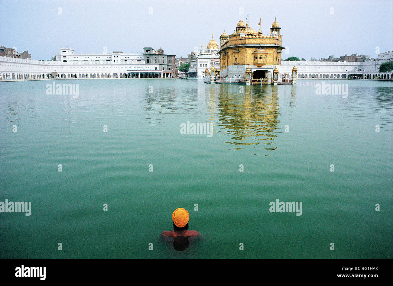 A lone Sikh pilgrim bathes at dawn in the water that surrounds the ...