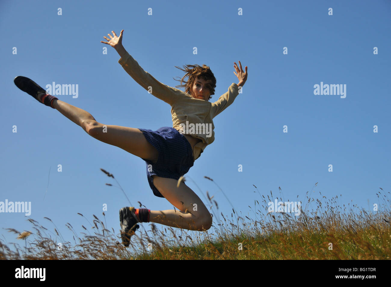 young white woman jumping and leaping on the dune arms up and legs in ...