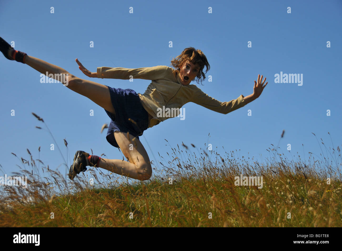 young white woman jumping and leaping on the dune arms up and legs in ...