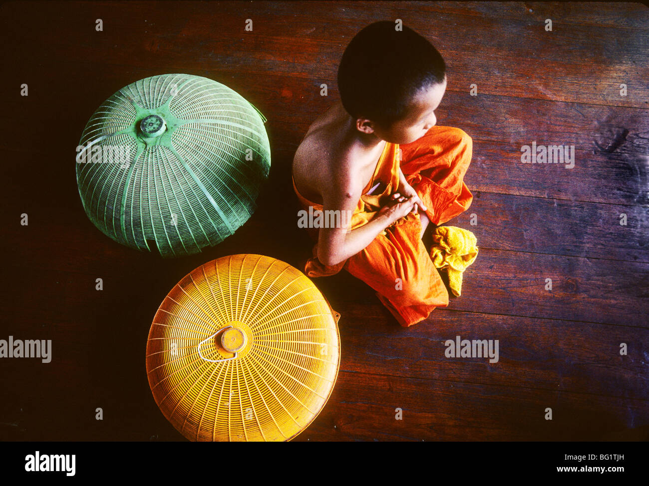 Young Thai monk kid sitting on wood floor meditating Stock Photo - Alamy