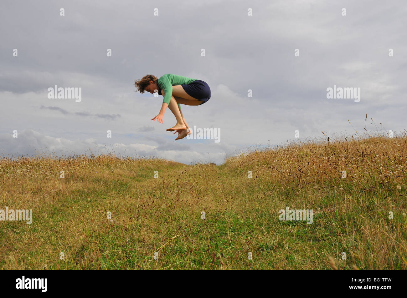 young white woman jumping and leaping on the dune arms and legs in air ...