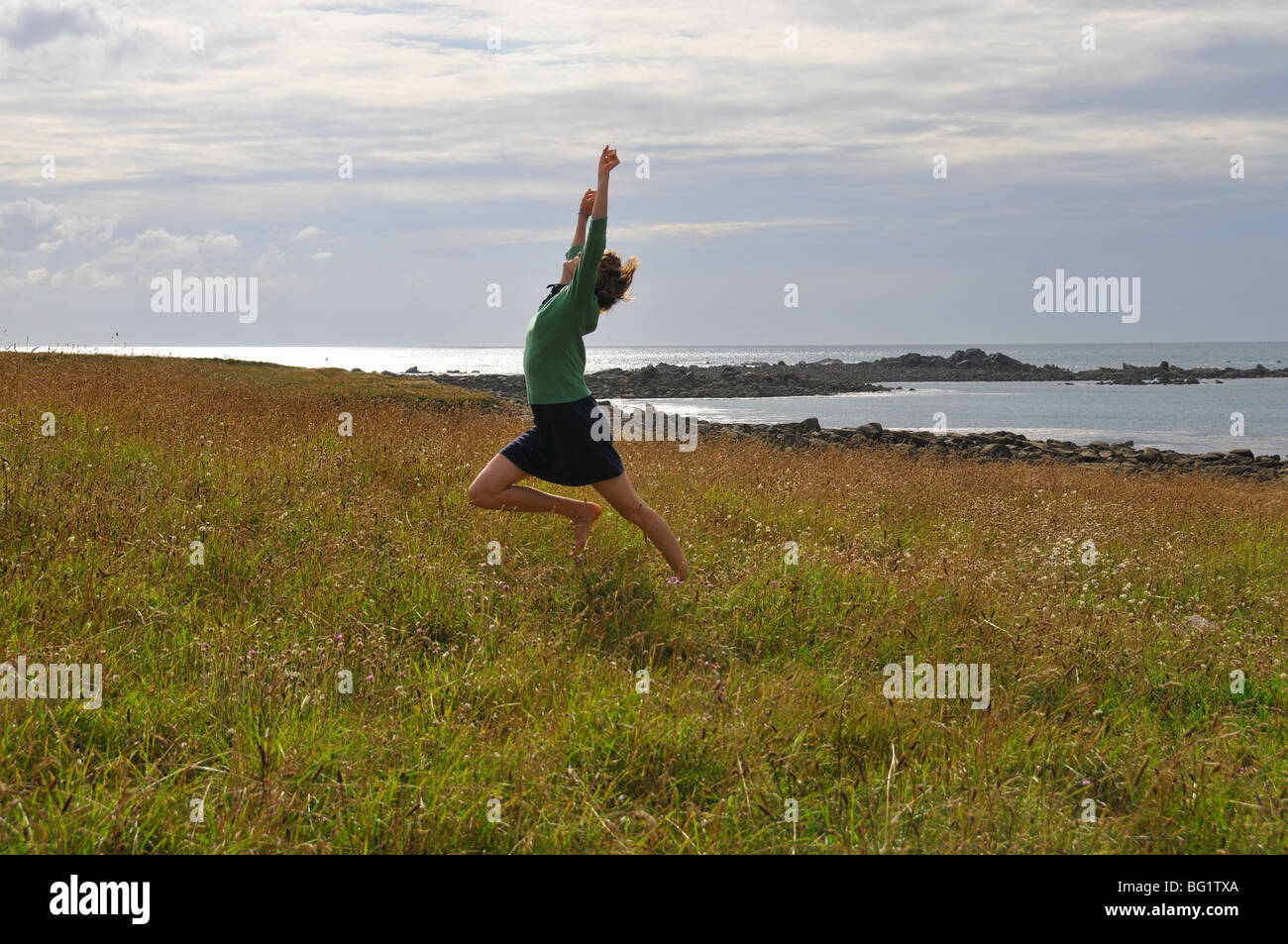 young white woman jumping and leaping on the dune arms up legs in air ...