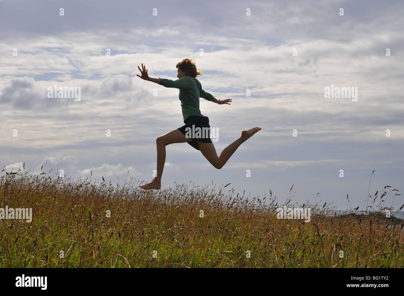young white woman jumping and leaping on the dune arms and legs in air ...